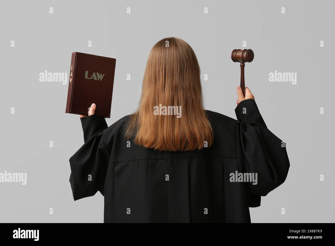 Teenage judge with gavel and law book on grey background, back view ...