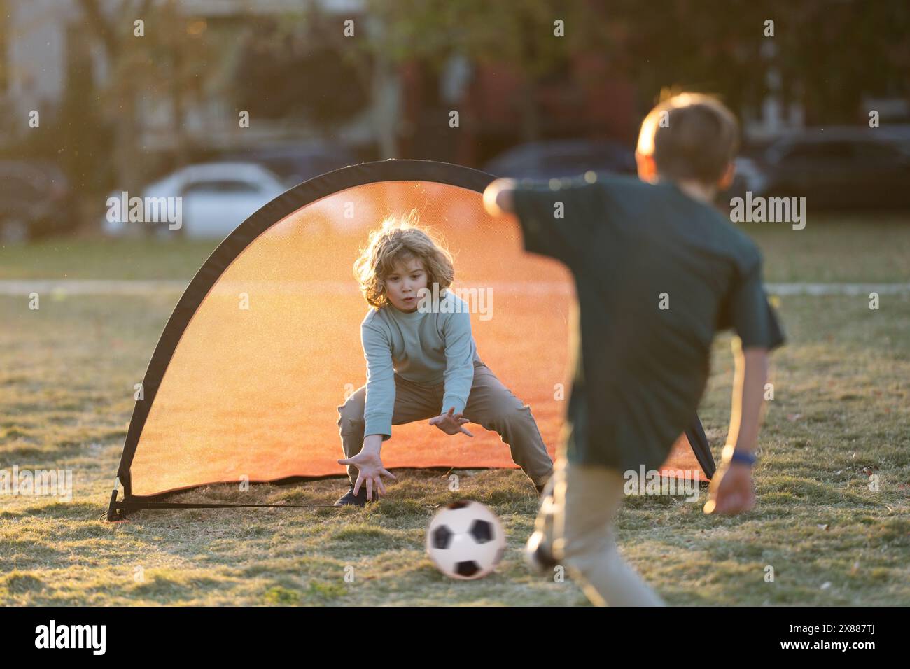 Kid Goalkeeper catches football ball during a football game. Football ...