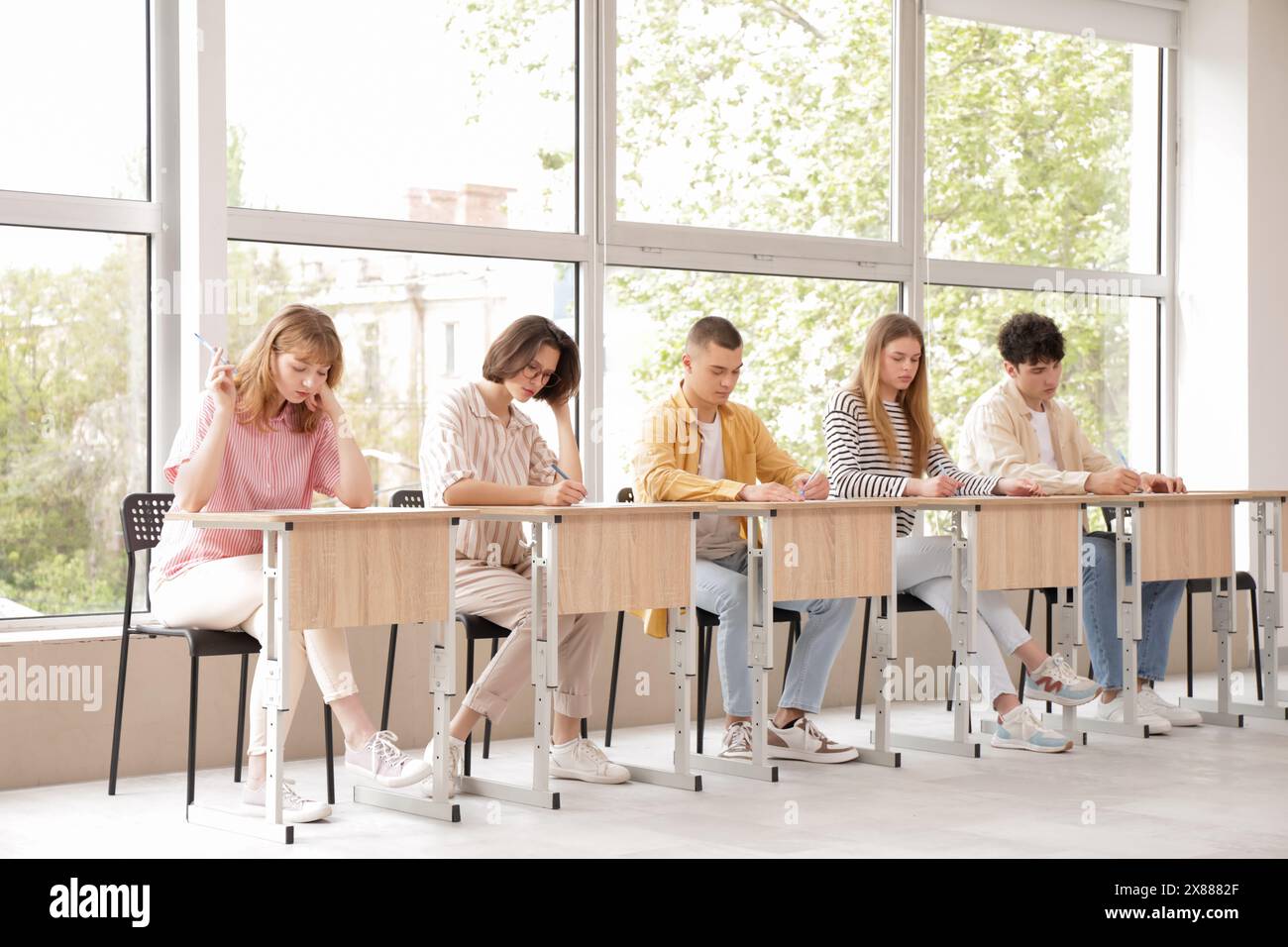Group of students passing exam in classroom Stock Photo - Alamy