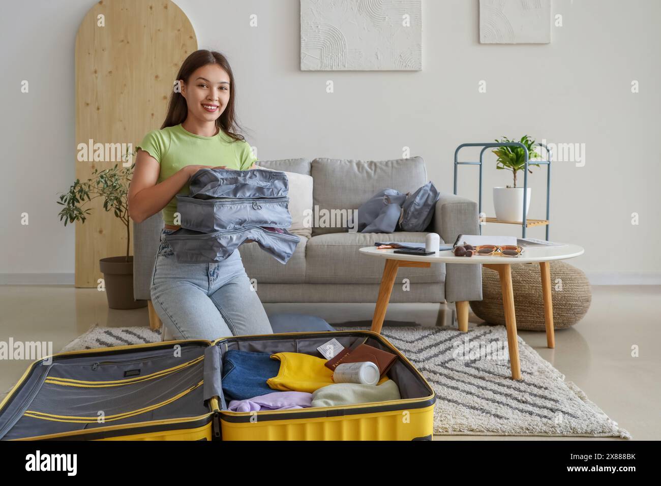 Female Asian traveler with organizers packing suitcase at home Stock ...