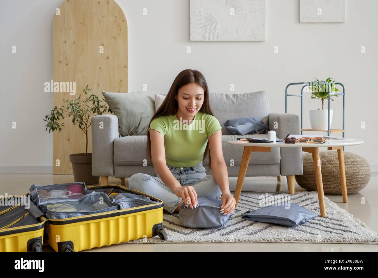 Female Asian traveler with organizer packing suitcase at home Stock ...