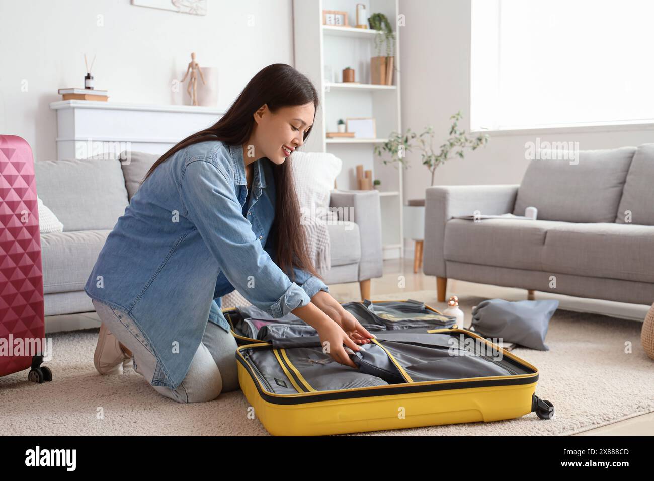 Female Asian traveler packing organizer into suitcase at home Stock ...