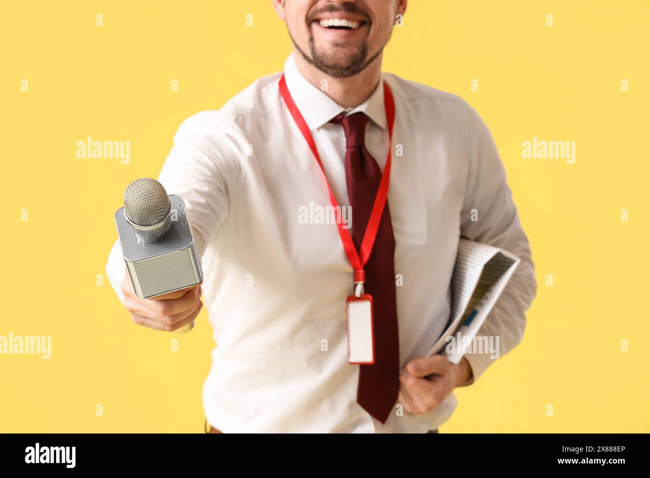 Male reporter with microphone and newspaper on yellow background ...
