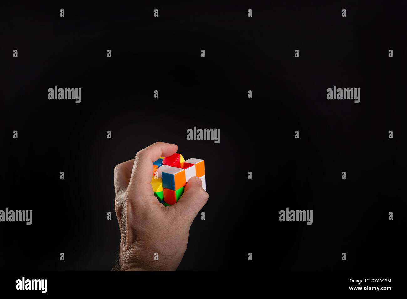 Salvador, Bahia, Brazil - May 15, 2024: Rubiks cube in a persons hands, portrait, black ...