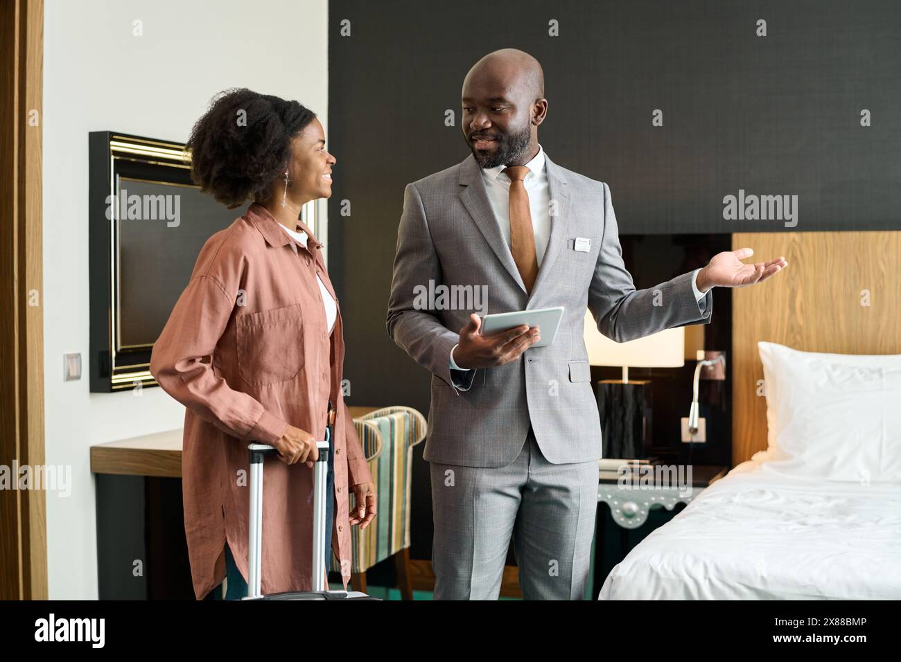 Portrait of luxury hotel manager welcoming young Black woman entering ...