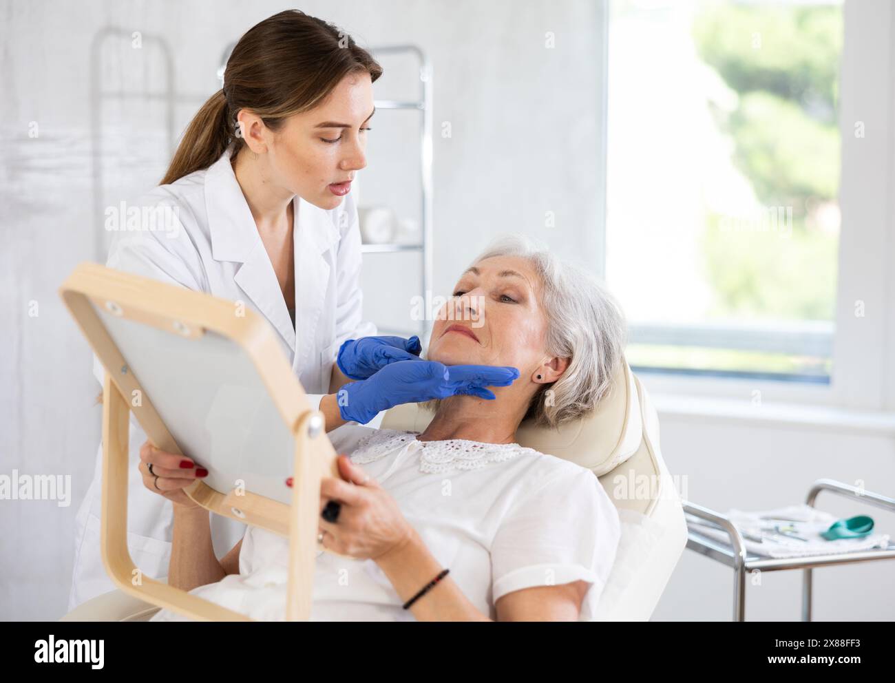 Elderly patient looking in mirror at clinic Stock Photo - Alamy