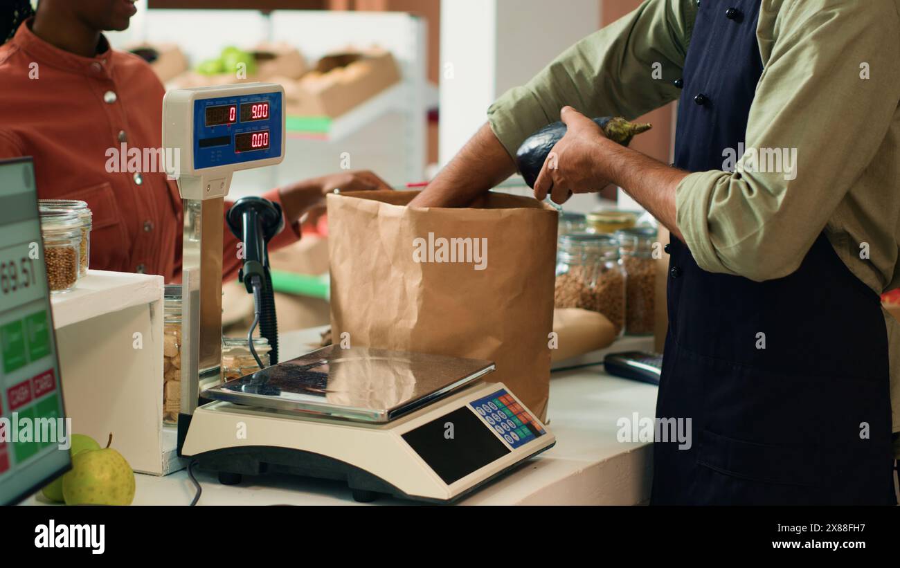 Vendor weighting fresh produce for buyer, placing fruits and veggies on ...