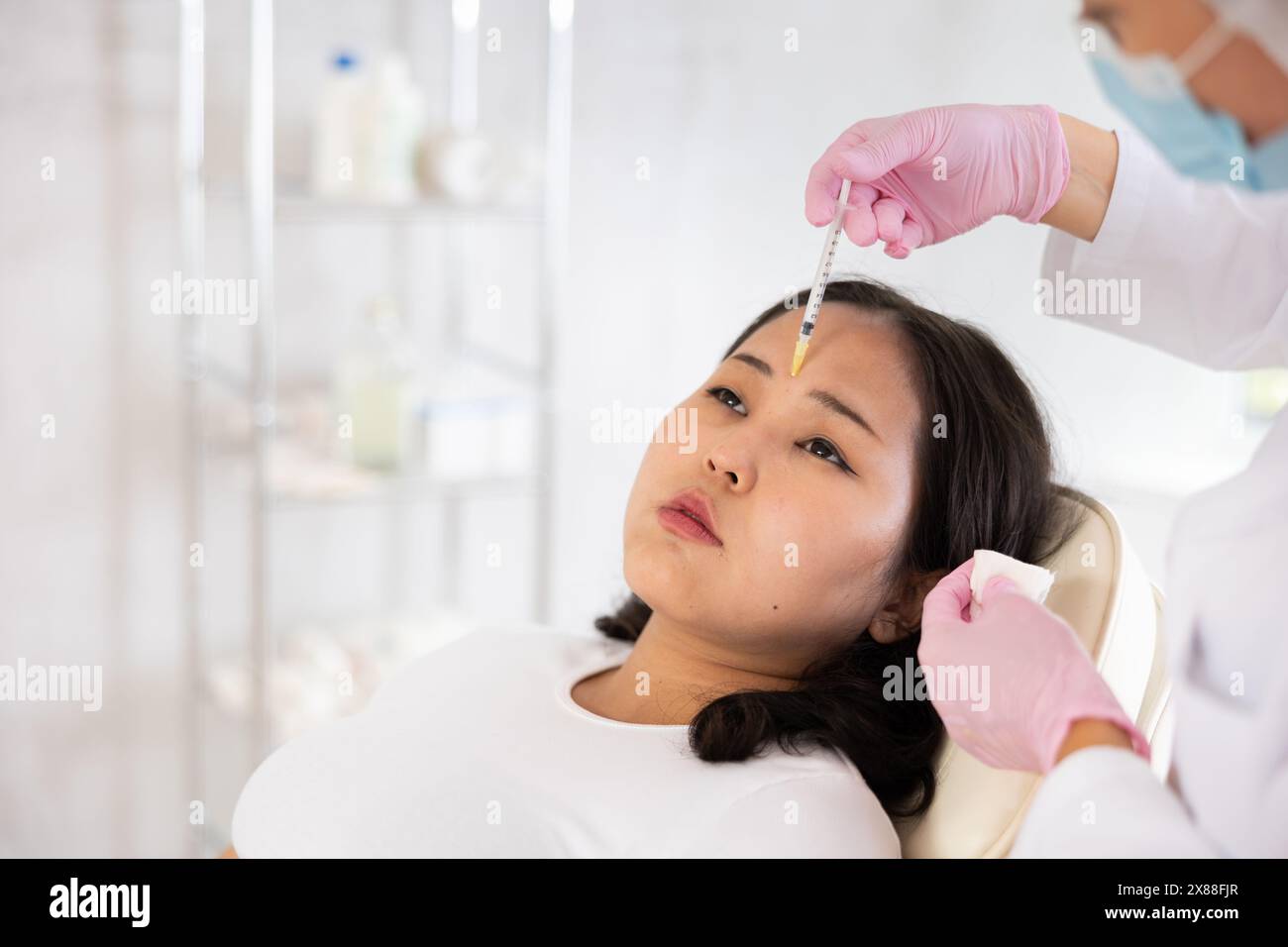 Face of young female client receiving injections during lip enhancement ...