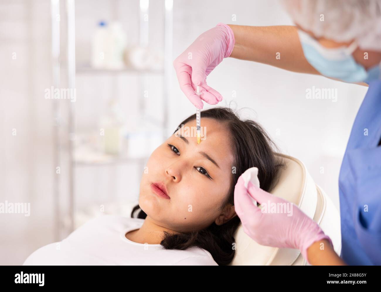 Face of young female client receiving injections during lip enhancement ...