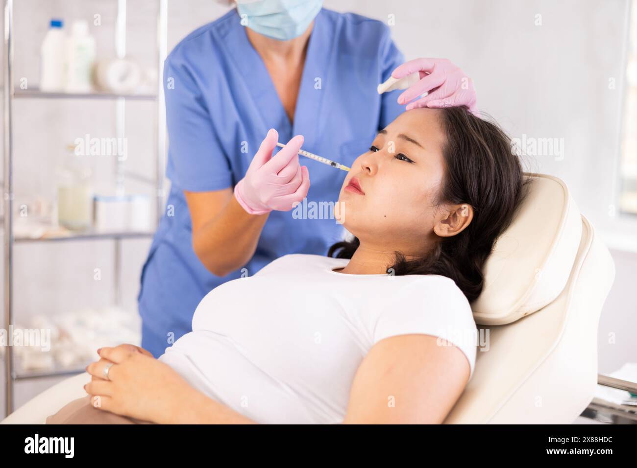 Face of young female client receiving injections during lip enhancement ...