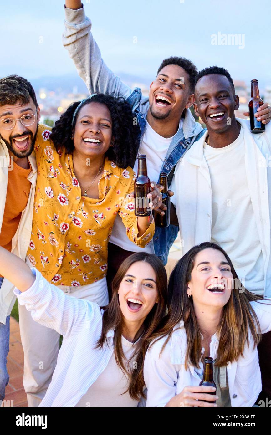 Group of diverse excited friends celebrating with beers at barbecue ...