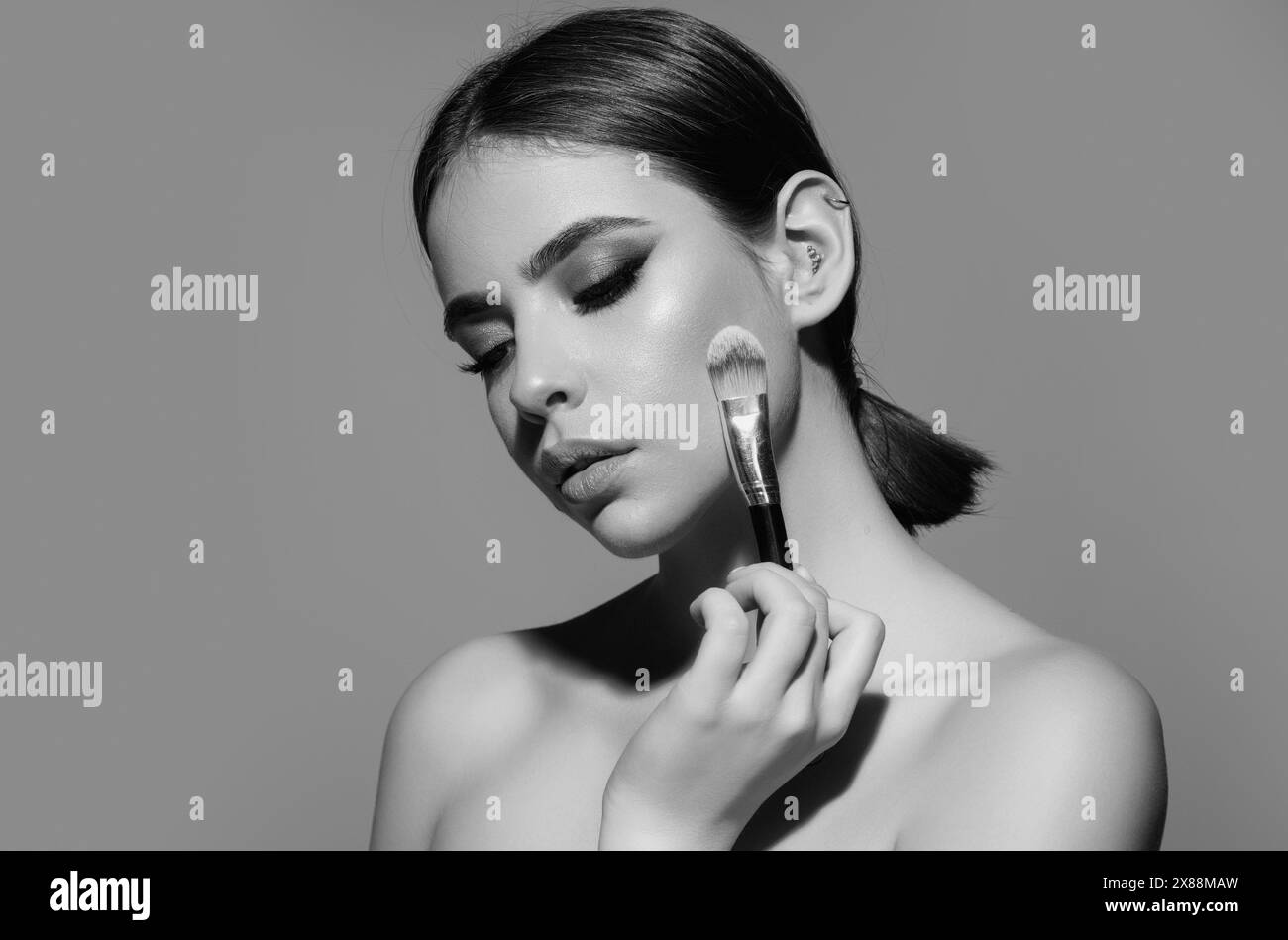 Young woman applies powder on the face using makeup brush. Beautiful ...