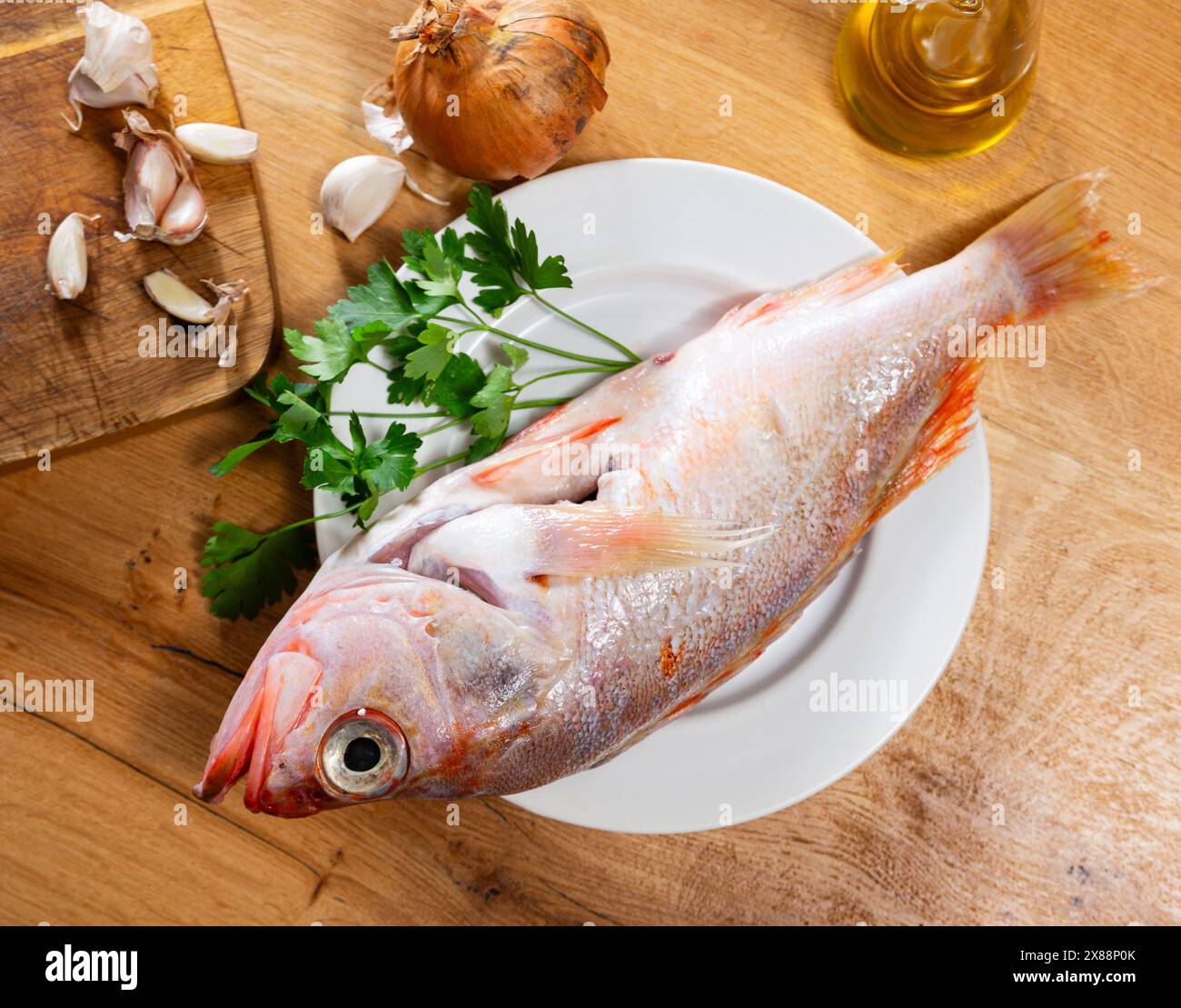 Raw whole red palometa fish with garlic and parsley on desk Stock Photo ...