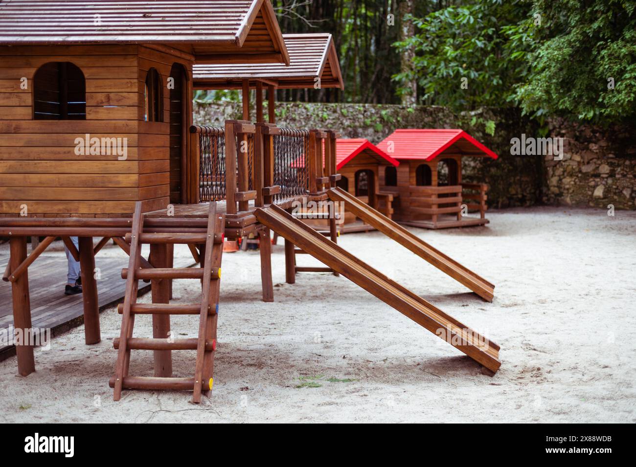 Children's wooden playhouse and slides in a sandy playground, inviting ...