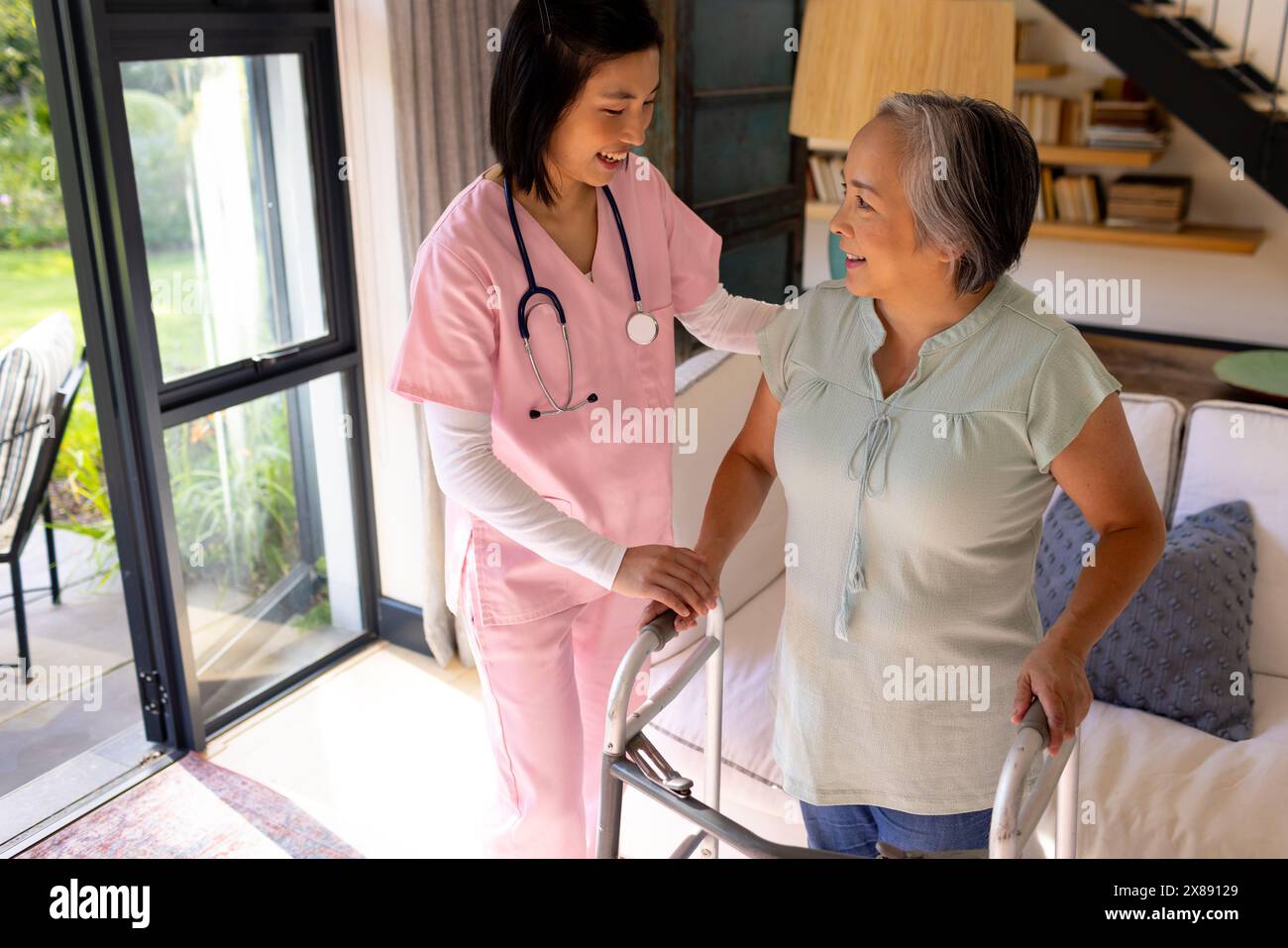 At home, Asian young female nurse and middle-aged patient using walker ...