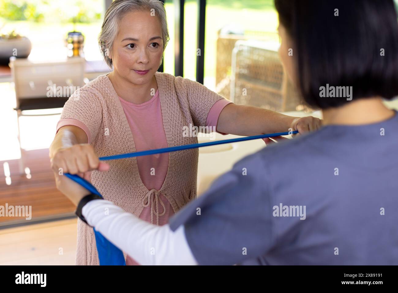 At home, Asian young female nurse and middle-aged patient using ...