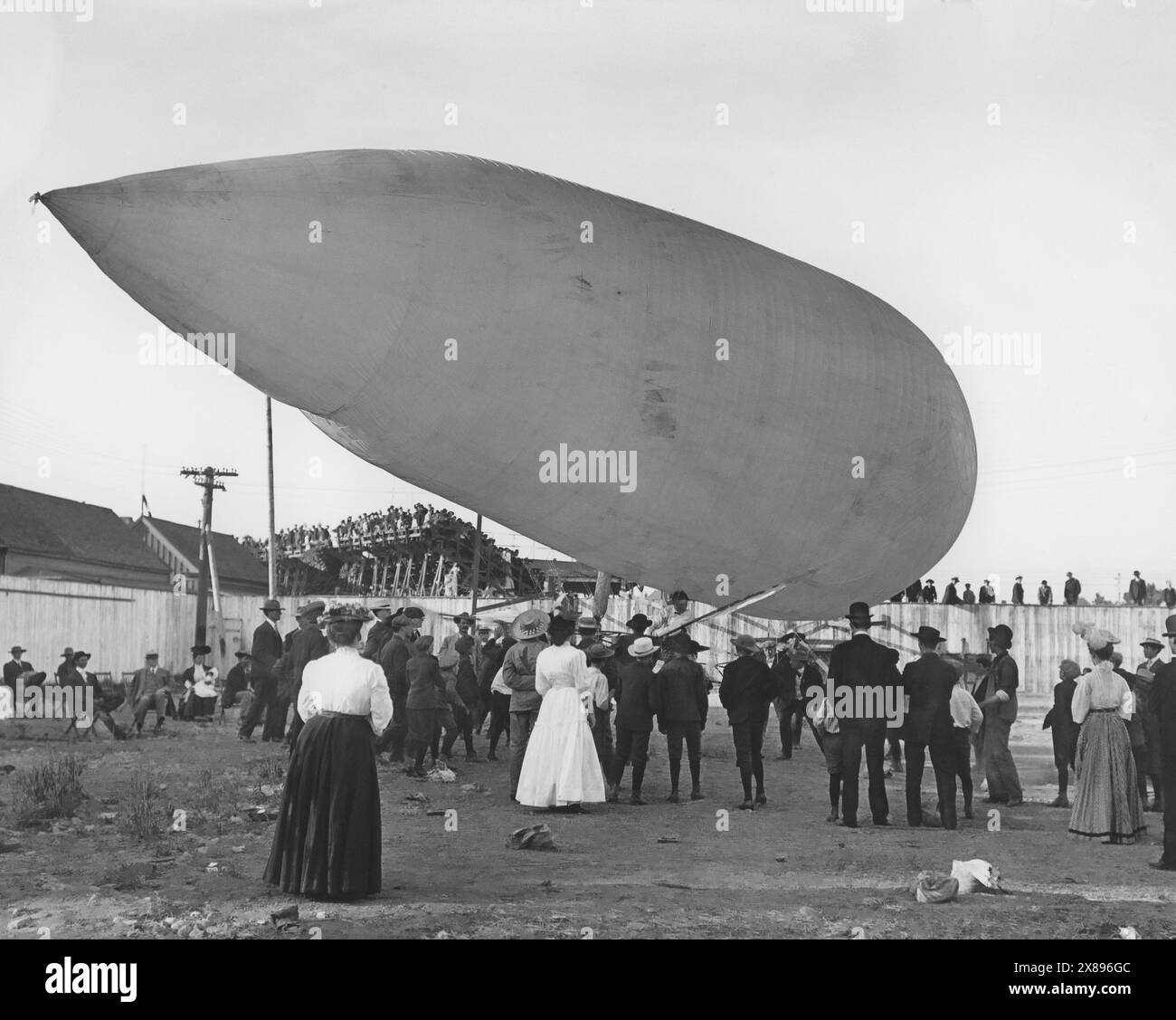 People standing around watching a small blimp being inflated at an ...