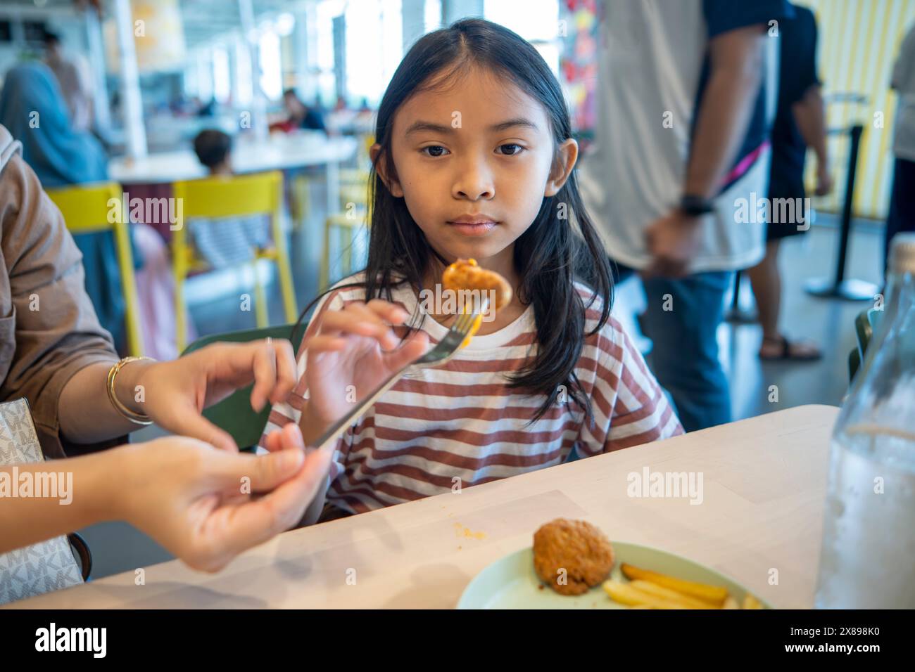 Asian little girl eating a chicken nugget at the restaurant Stock Photo ...