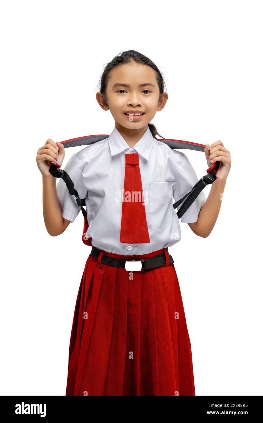 Cheerful young girl stands proudly in her red and white school uniform ...