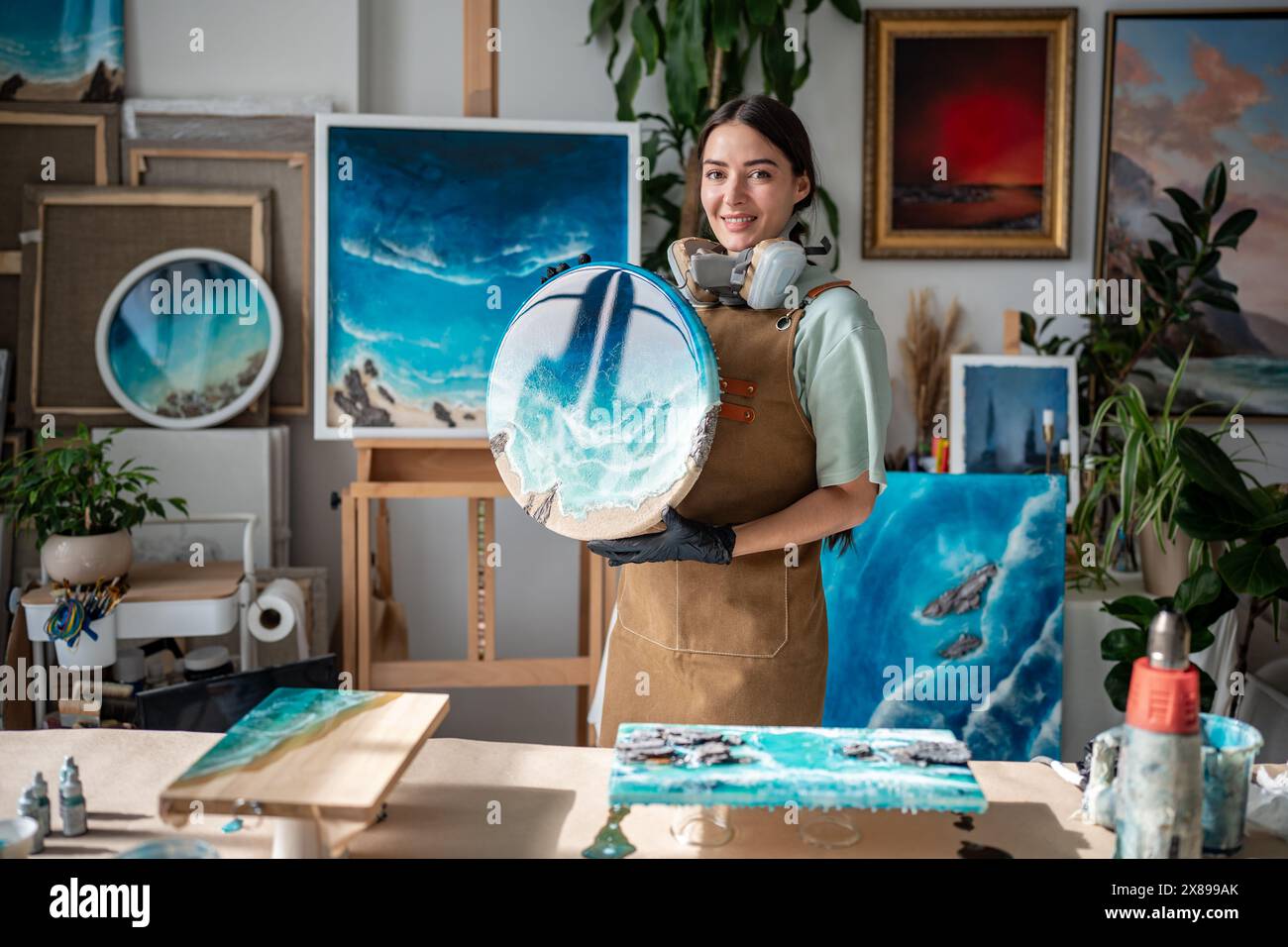 Happy woman artist in gloved, aproned holds finished epoxy resin ...