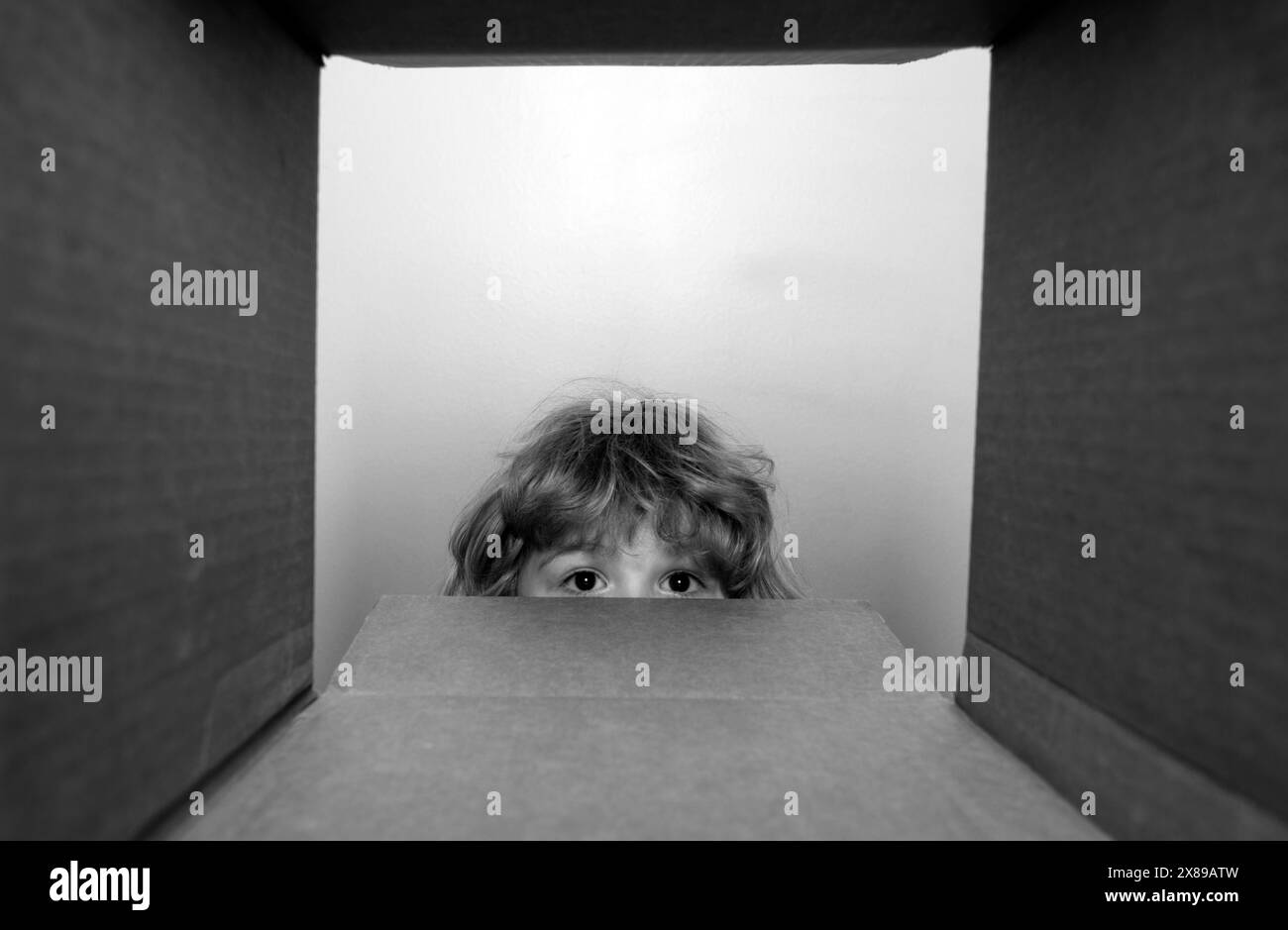 Child boy looking surprised into a gift. Cheerful cute child opening a ...
