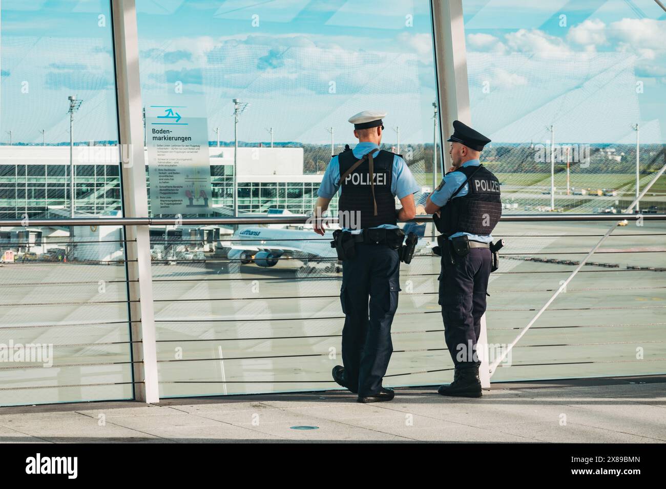 Two armed airport police officers watching over a taxiway at Munich ...