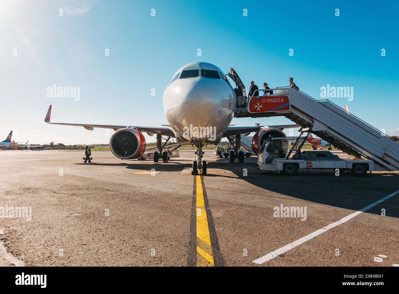 a front-on shot of an Airbus A320 passengers board via stairs on the ...