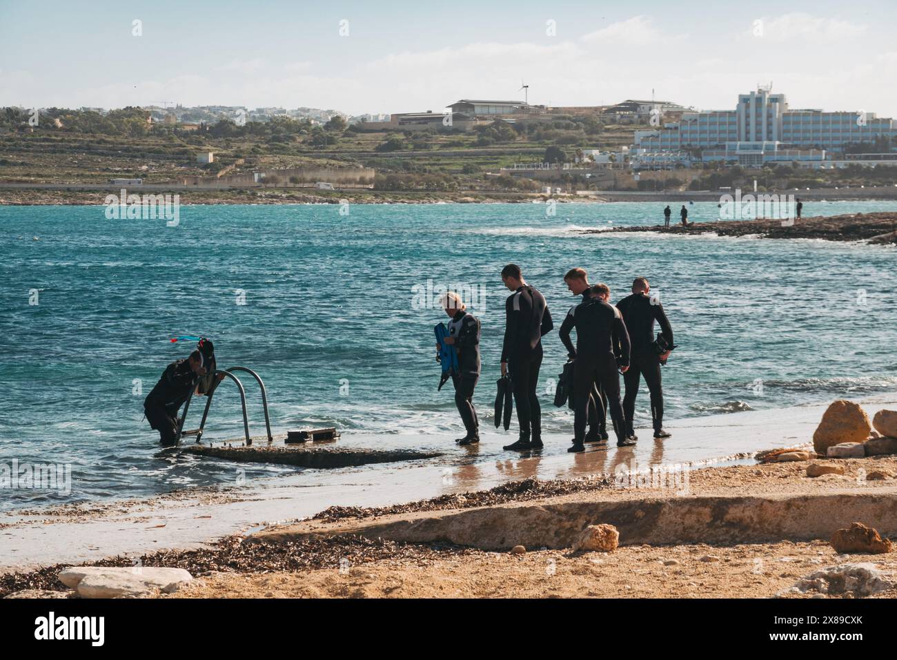 scuba divers descending into the ocean via a ladder at Qawra Point ...