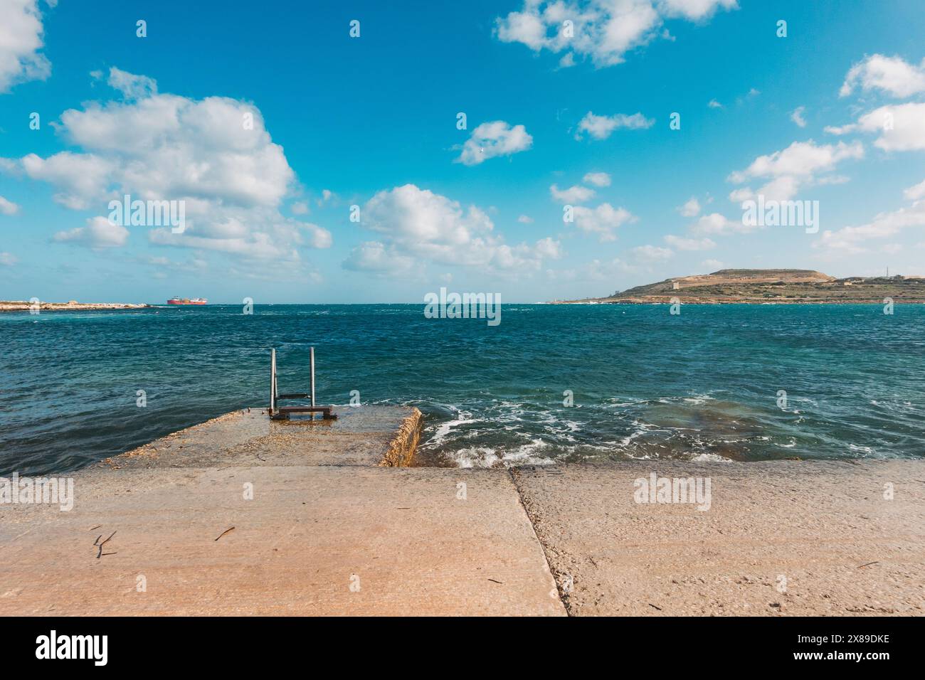 a metal ladder descends into the sea on a concrete sea break at Qawra ...