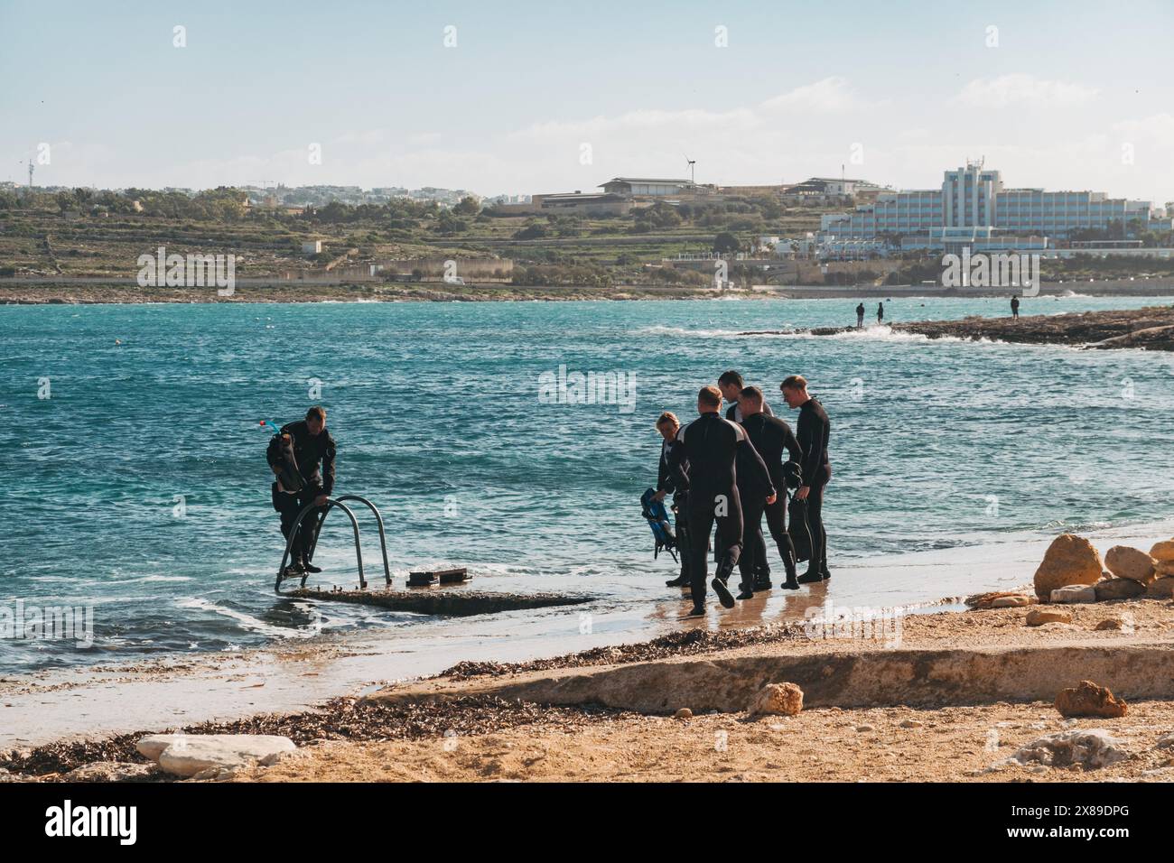 scuba divers descending into the ocean via a ladder at Qawra Point ...