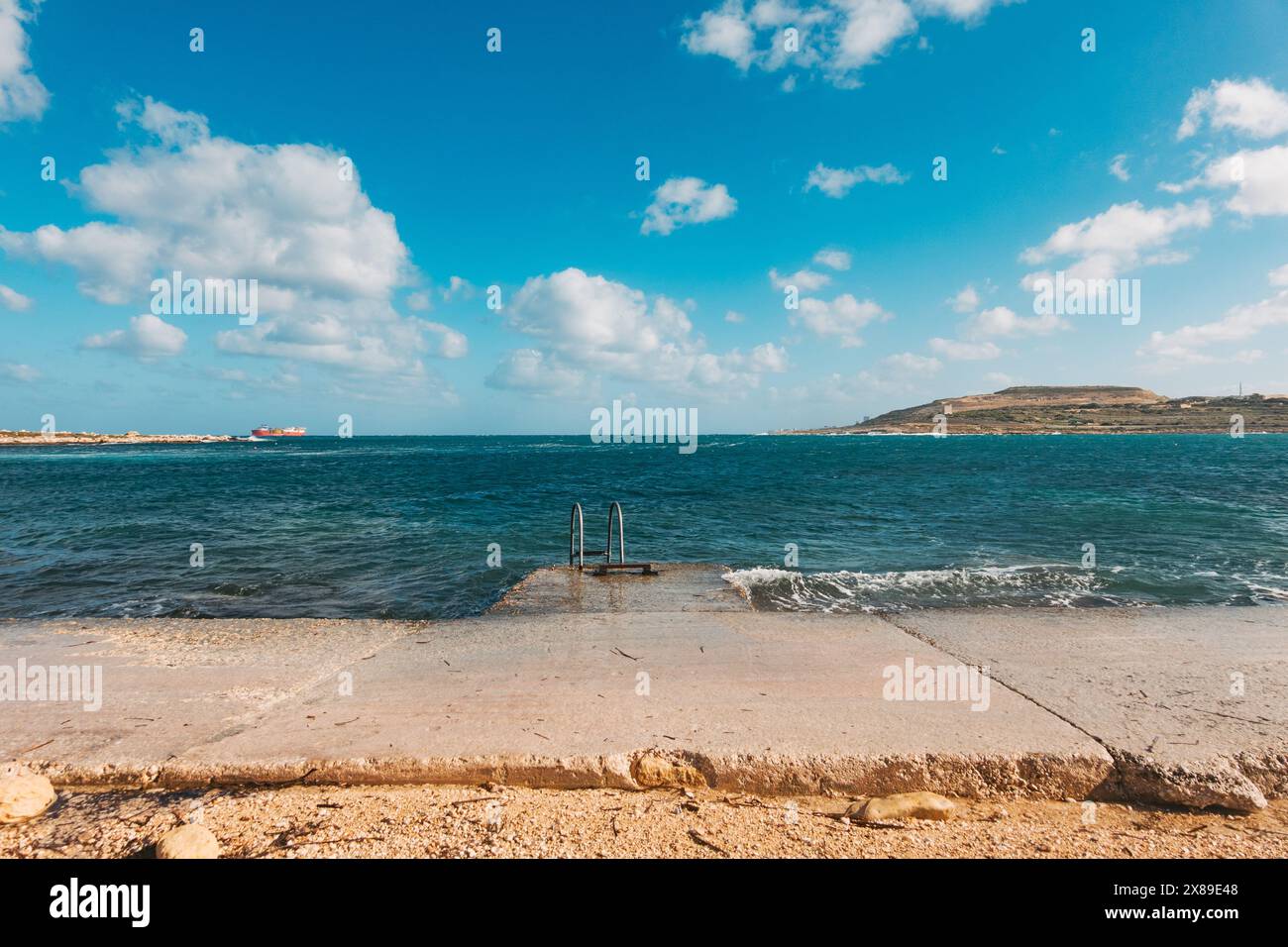 a metal ladder descends into the sea on a concrete platform at Qawra ...