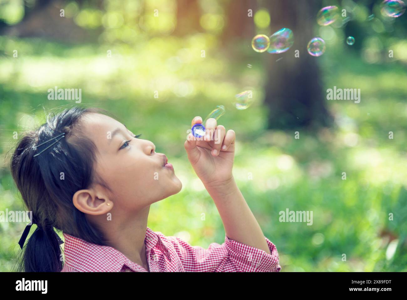 Adorable happy cute girl playful foam bubbles in green playground in ...