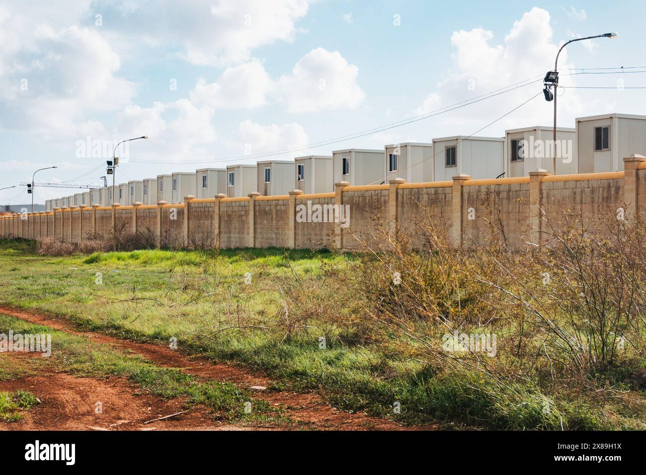 Container housing units behind a wall at the Ħal Far Open Centre, a ...