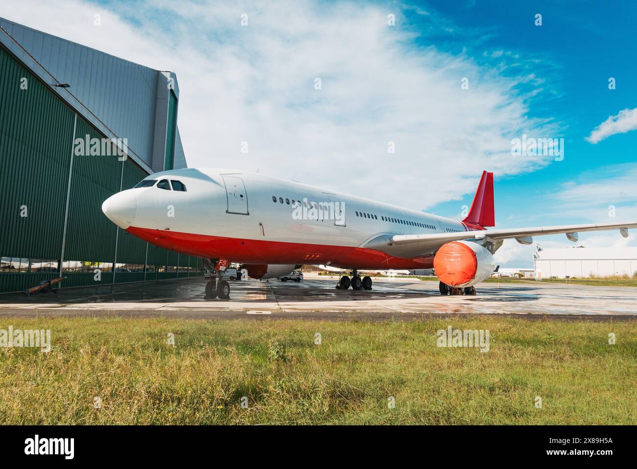 An unmarked Airbus A330 with engine covers parked in for maintenance at ...