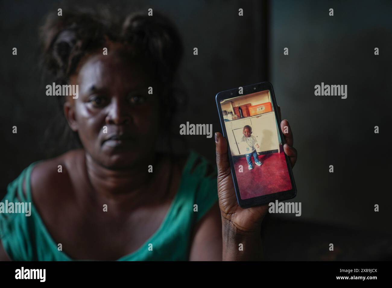 Mildred Banda holds a phone showing a picture of her one-year-old son ...