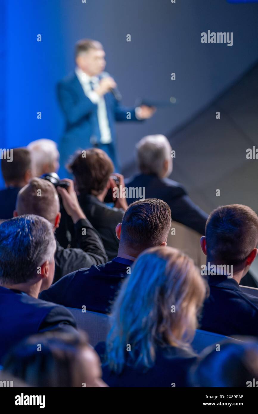 Speaker is addressing an audience at a business conference. People in ...