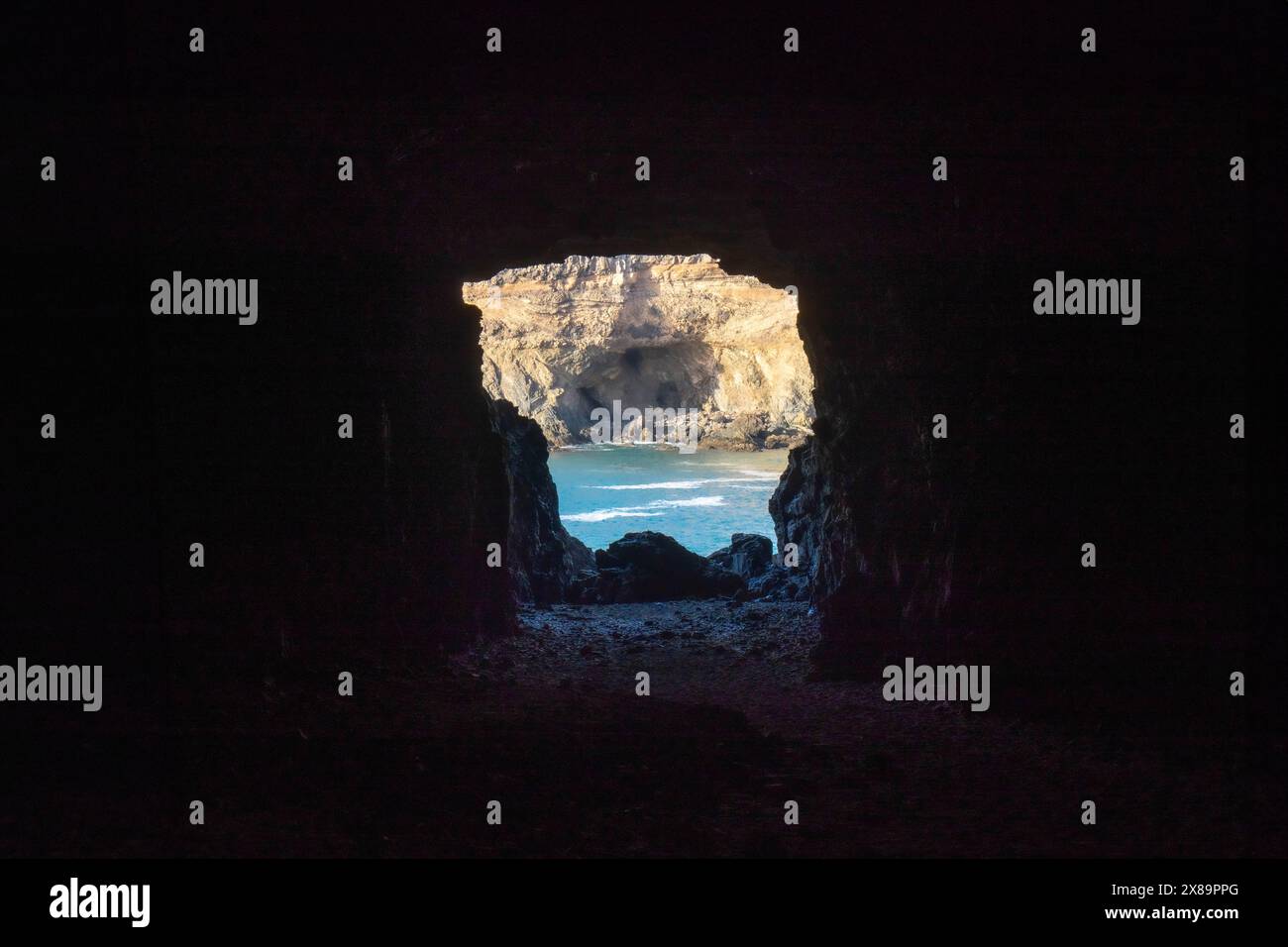 A breathtaking cave opening reveals a stunning view of a serene body of ...