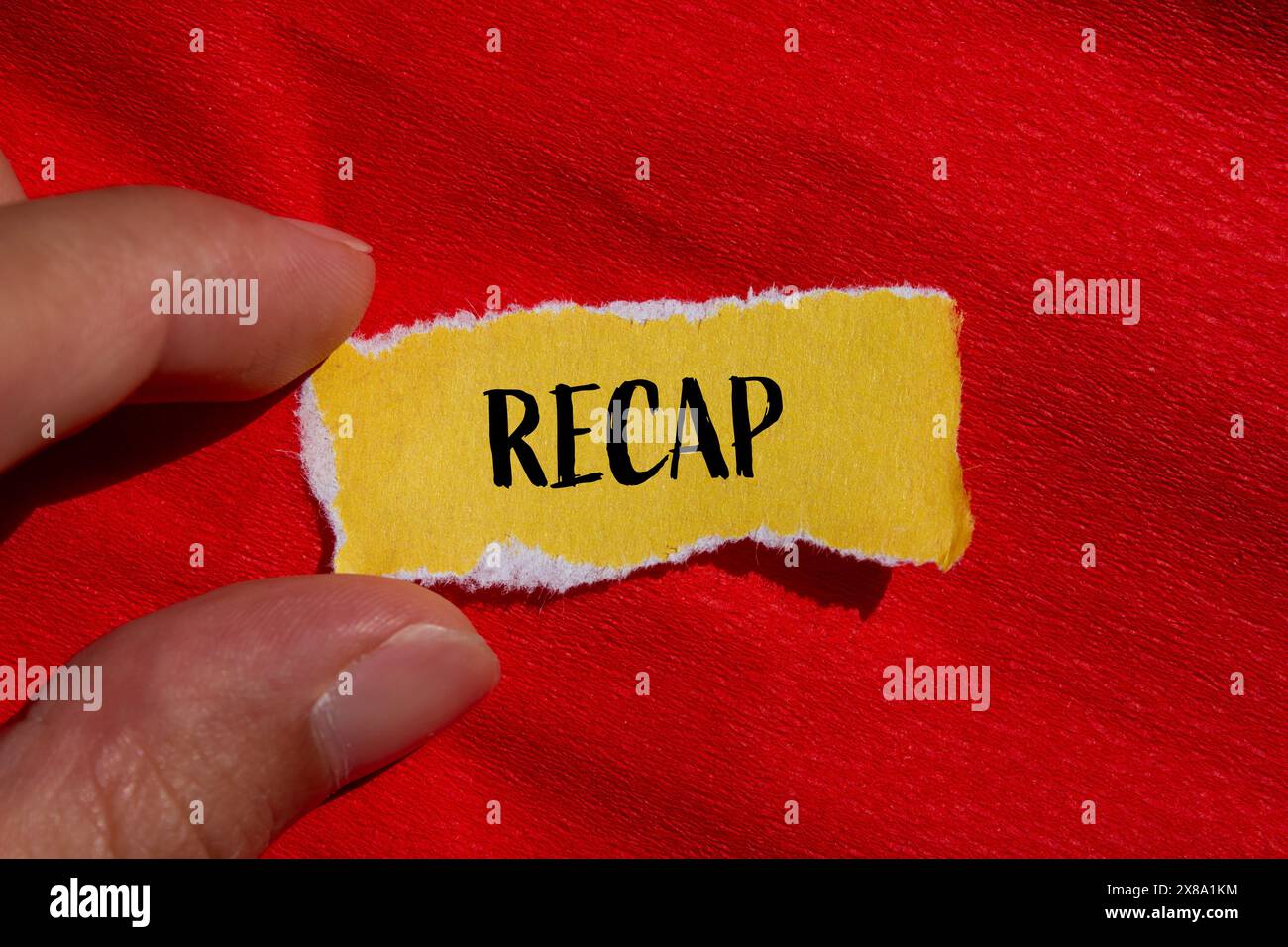 Recap word written on ripped yellow paper piece with red background ...