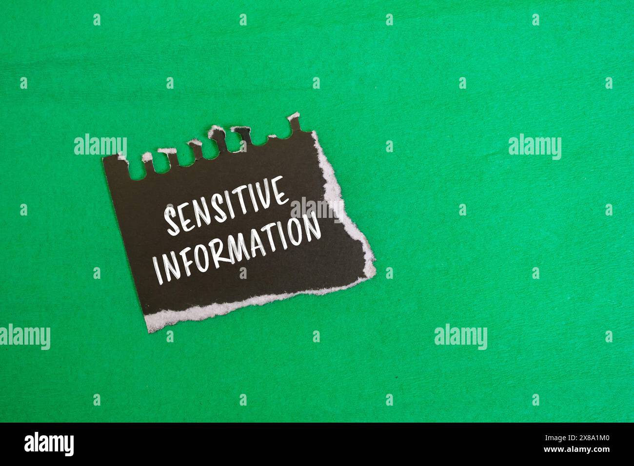 Sensitive information words written on ripped black paper piece with ...