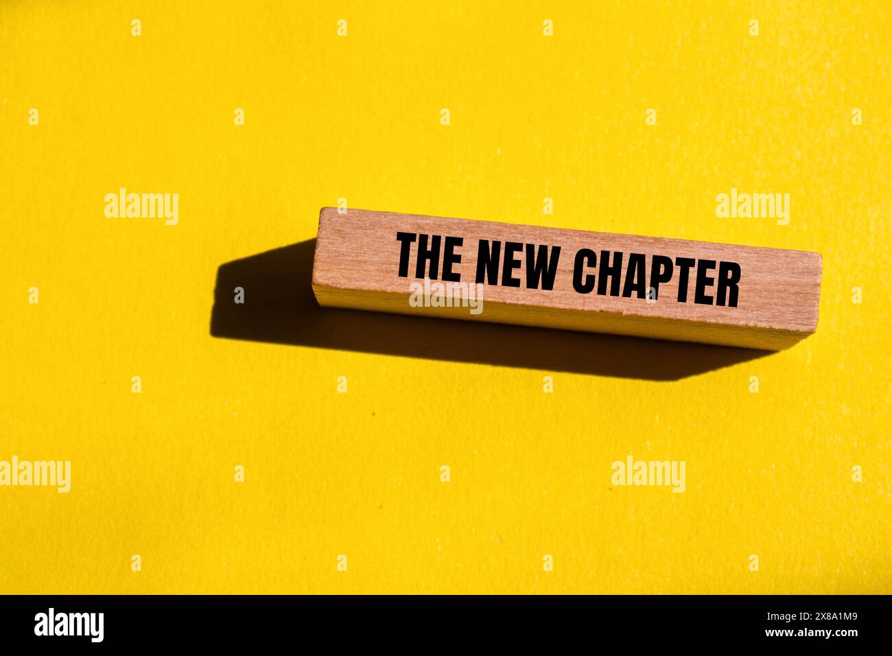 The new chapter words written on wooden block with yellow background ...
