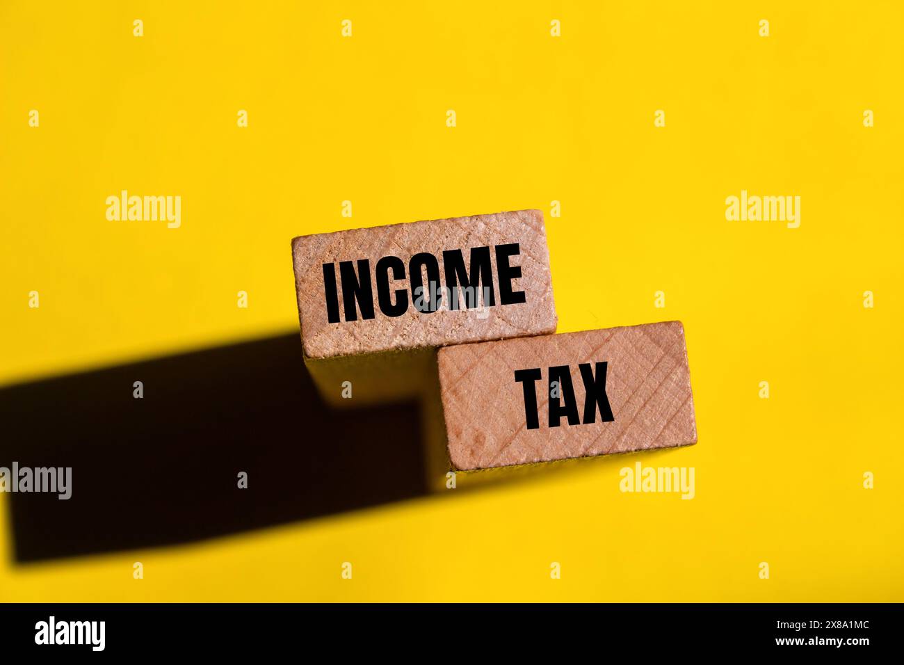 Income tax words written on wooden blocks with yellow background ...