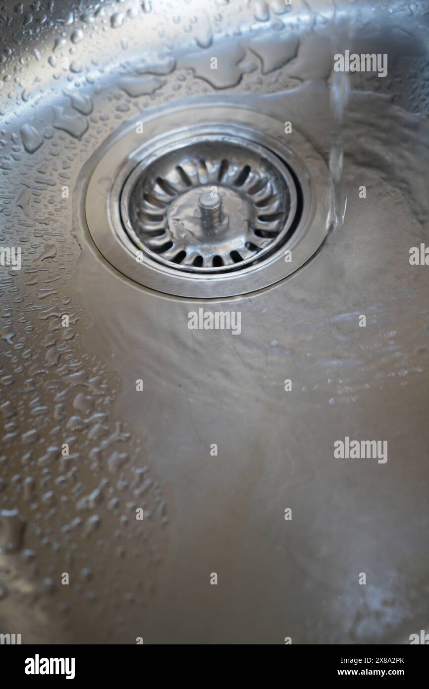 Stainless steel sink and water drain in a modern kitchen, water flow in ...