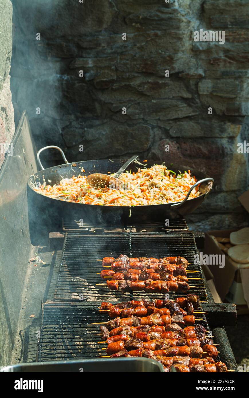 A BBQ grill with various types of food cooking on top of it. The flames ...