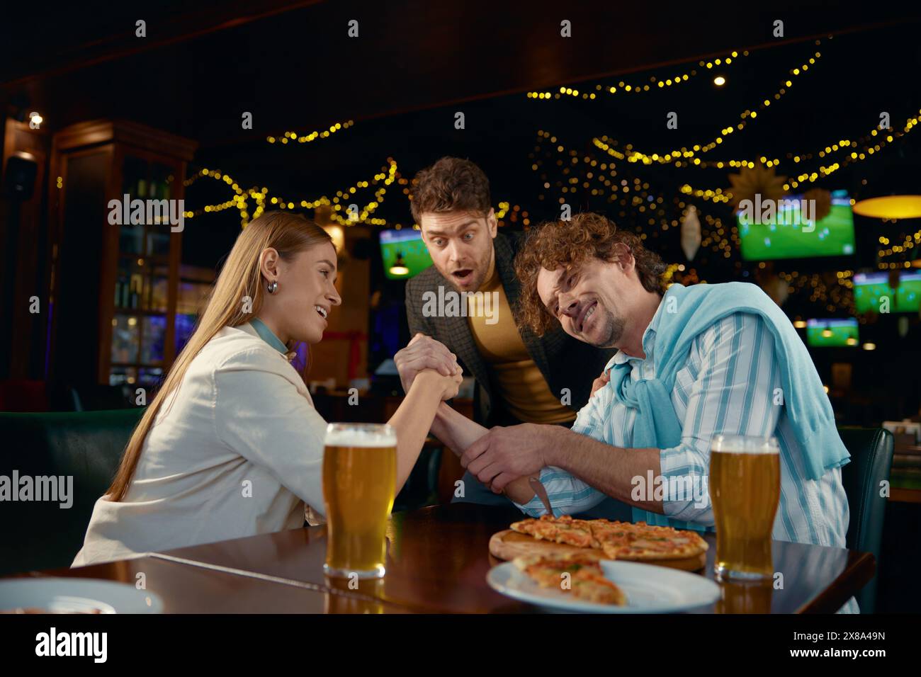 Cheerful friends having fun arm wrestling during rest in pub Stock ...