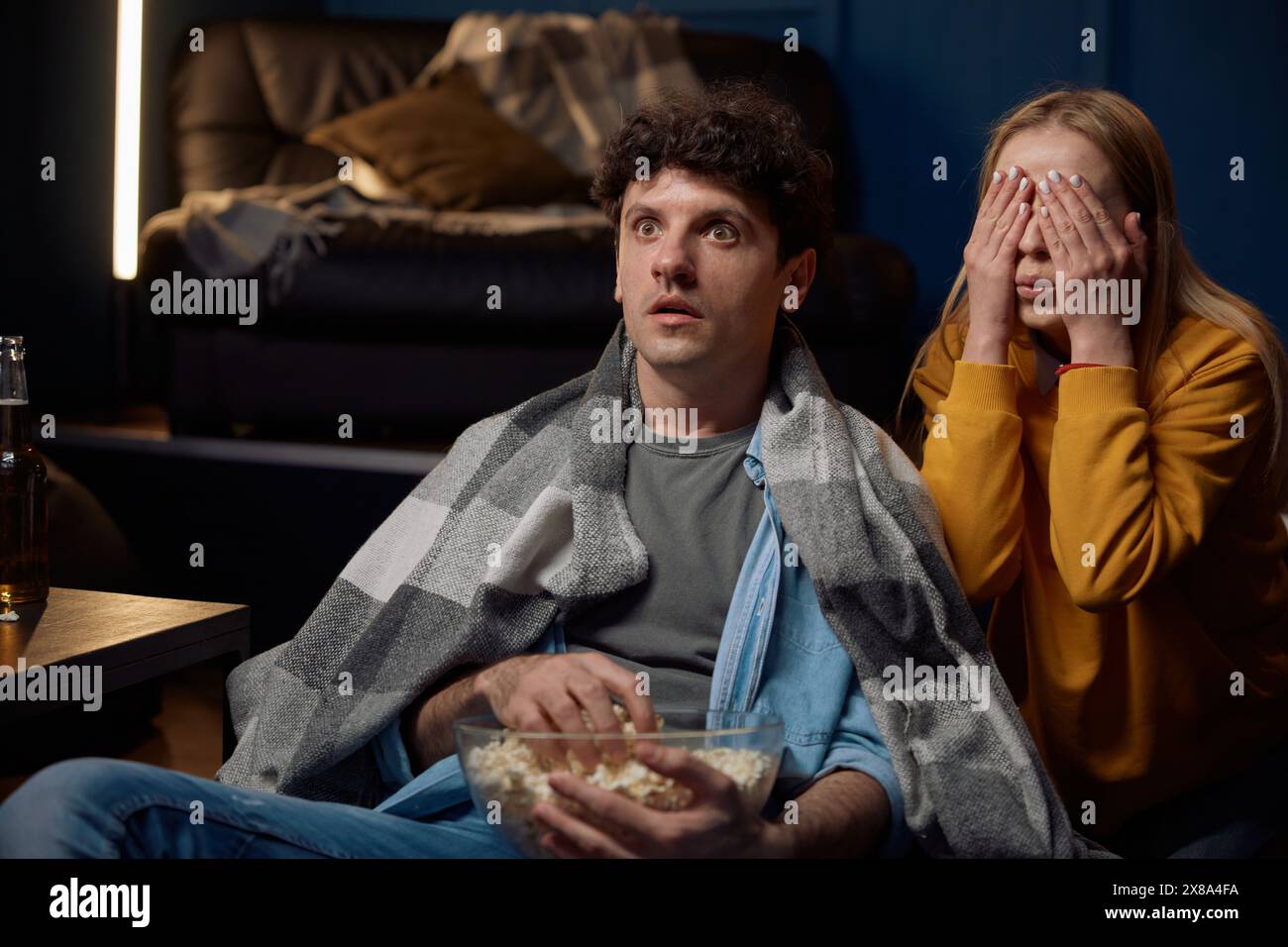 Young couple watching scary movie together Stock Photo - Alamy