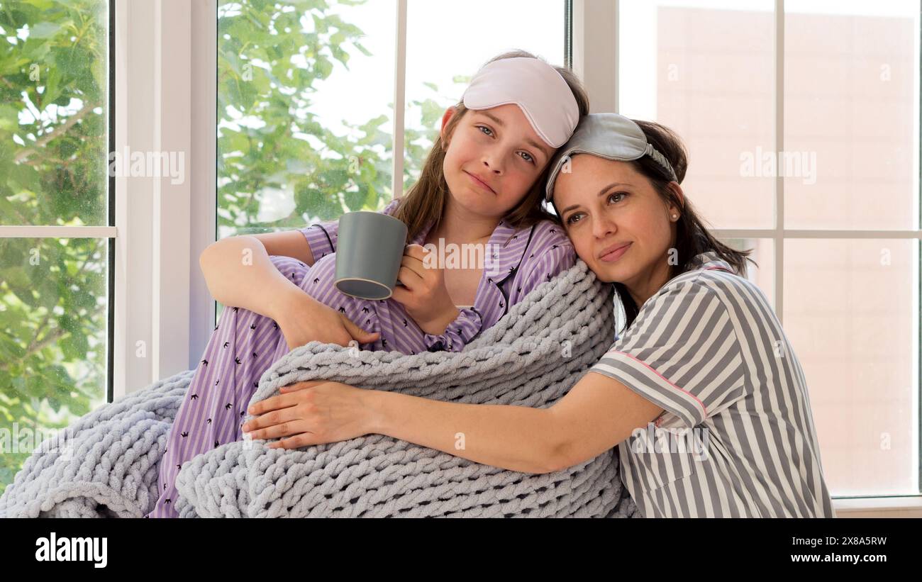 Mother and daughter enjoying a quiet moment by the window. Common cold ...