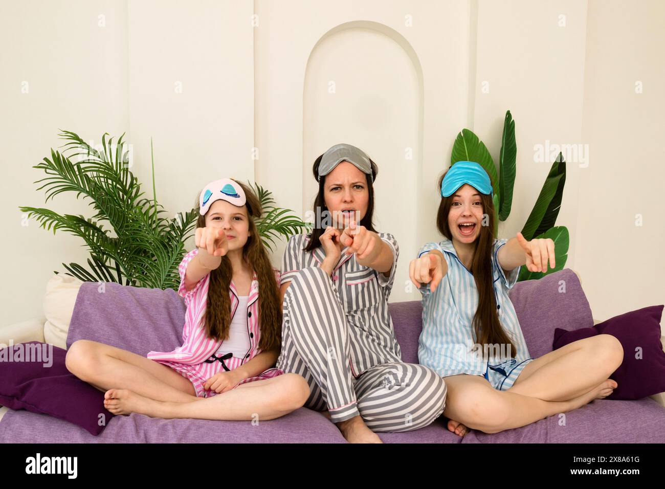 Family pointing and laughing together on couch. Atmosphere of joy and ...