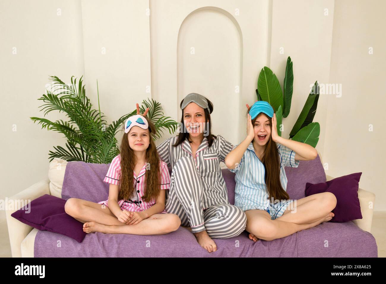 Mother and daughters sitting on couch with surprised expressions ...