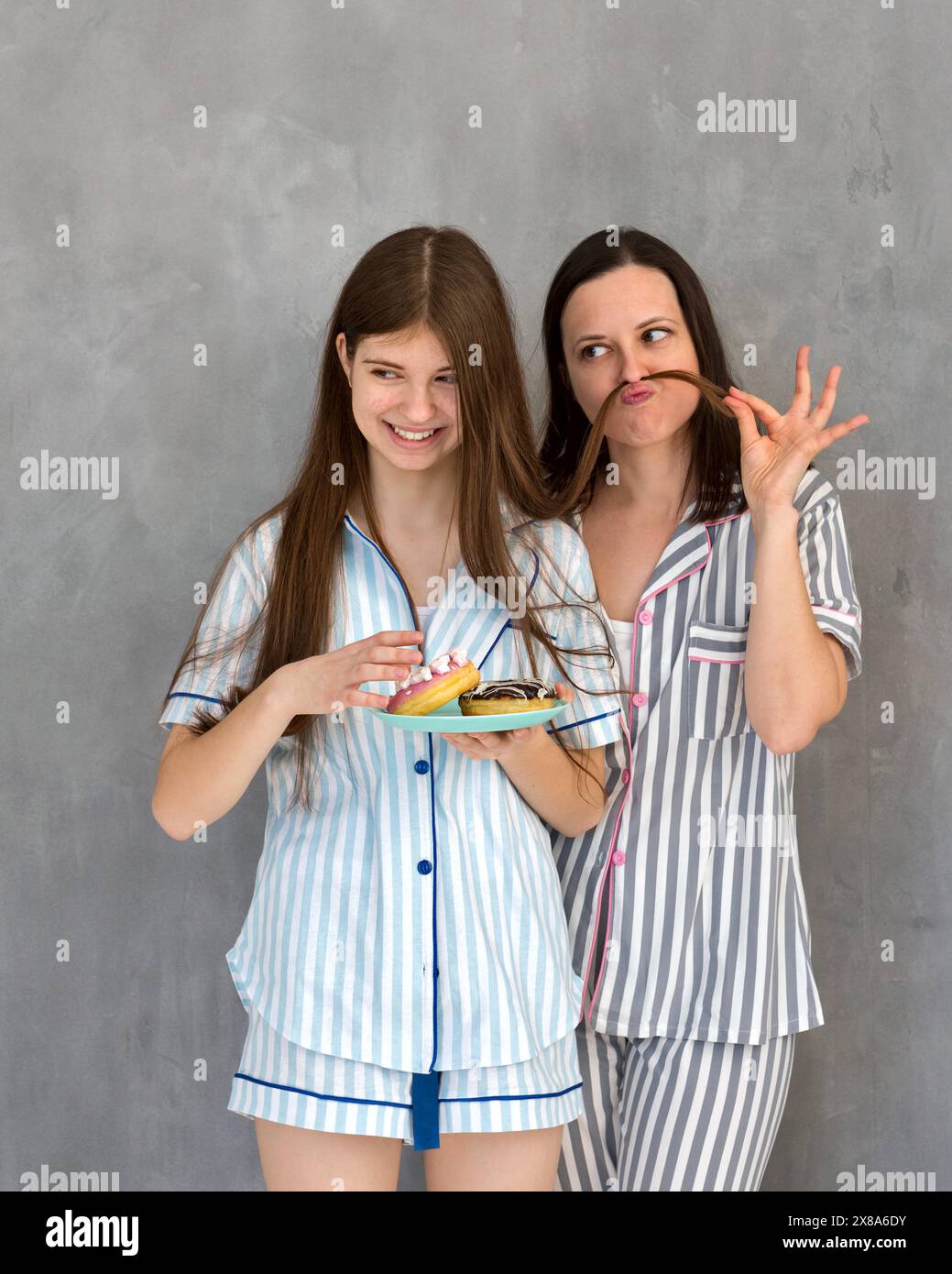 Mother and daughter in pajamas making funny faces with pastry. Family ...