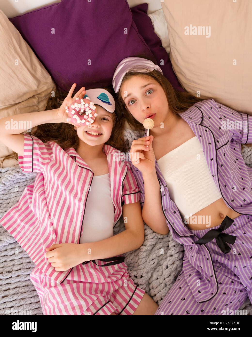 Two girls in pajamas enjoying sweets at a colorful sleepover ...